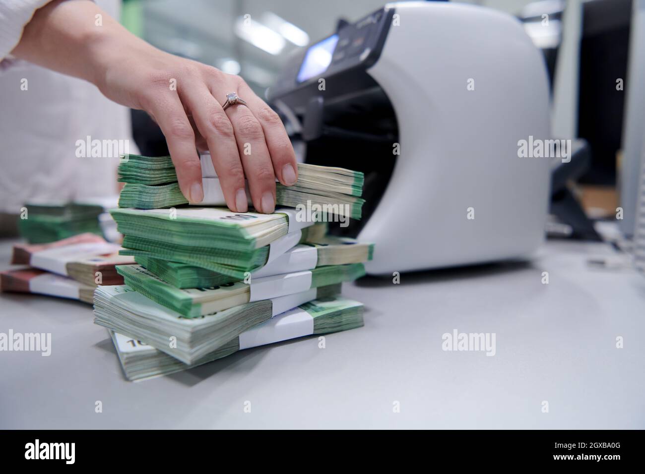 Bank employees using money counting machine while sorting and counting ...