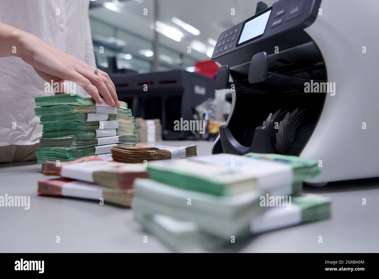 Bank employees using money counting machine while sorting and counting ...