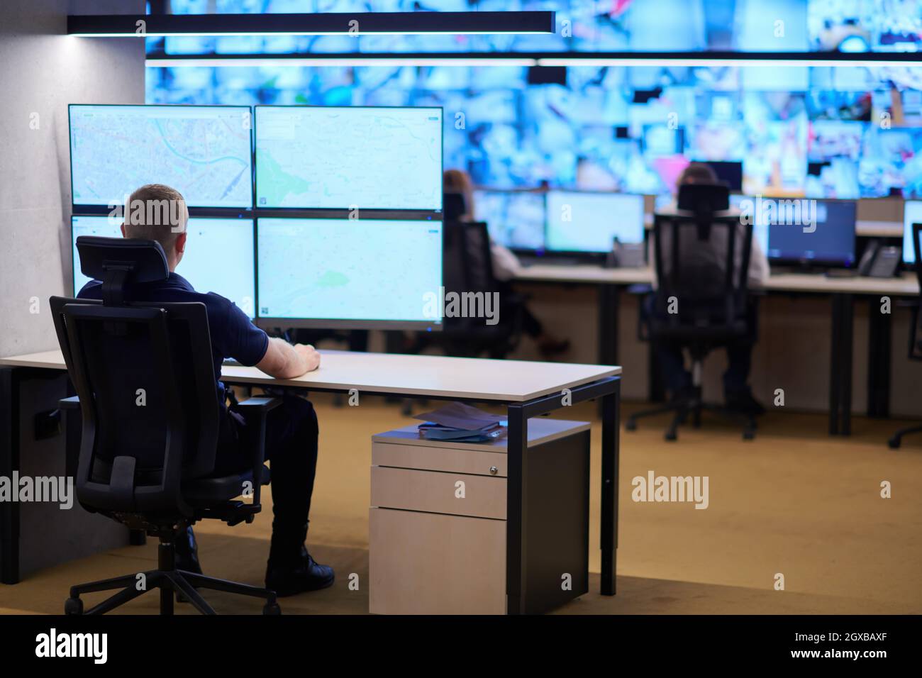 Male security operator working in a data system control room offices ...