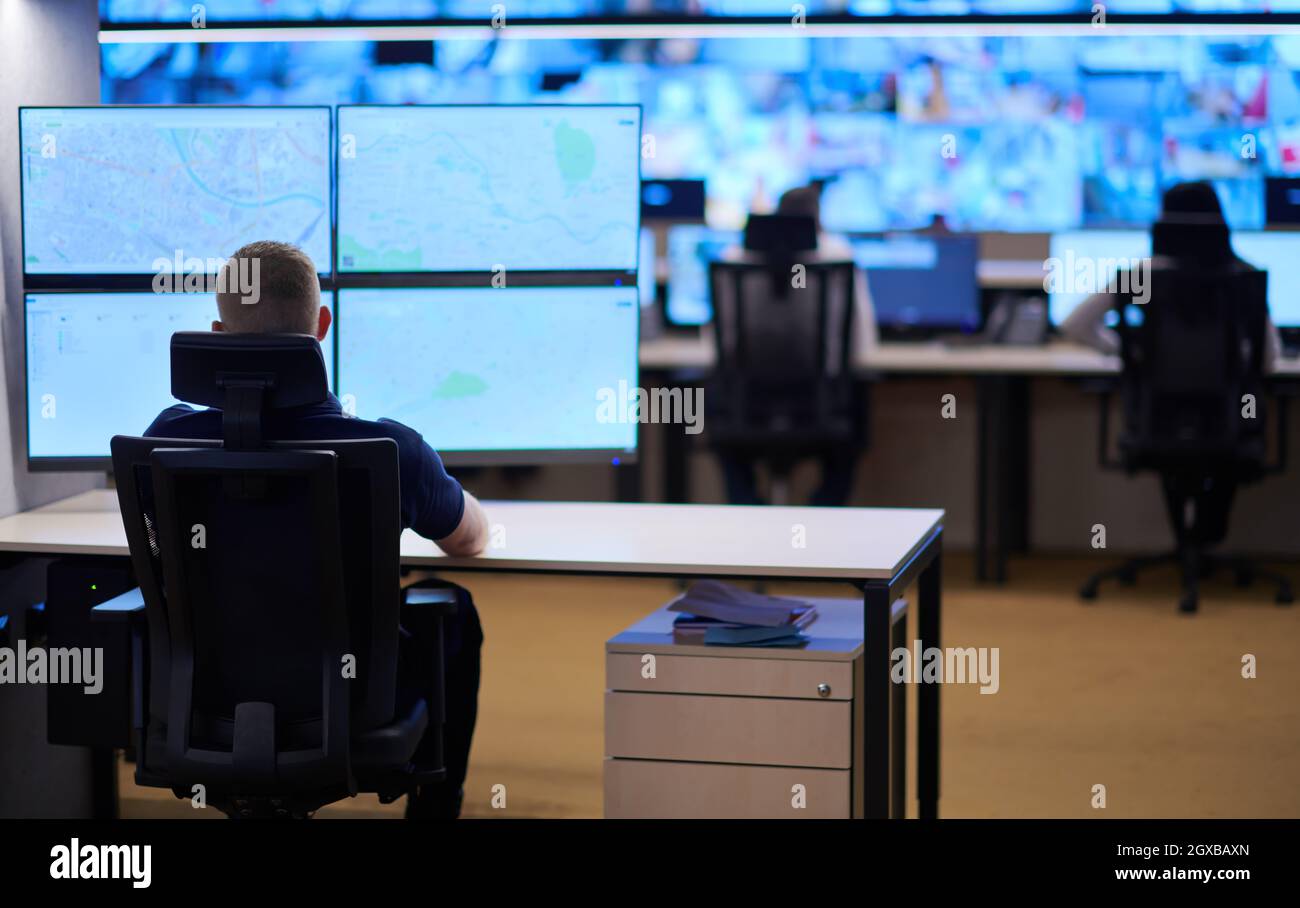 Male security operator working in a data system control room offices ...
