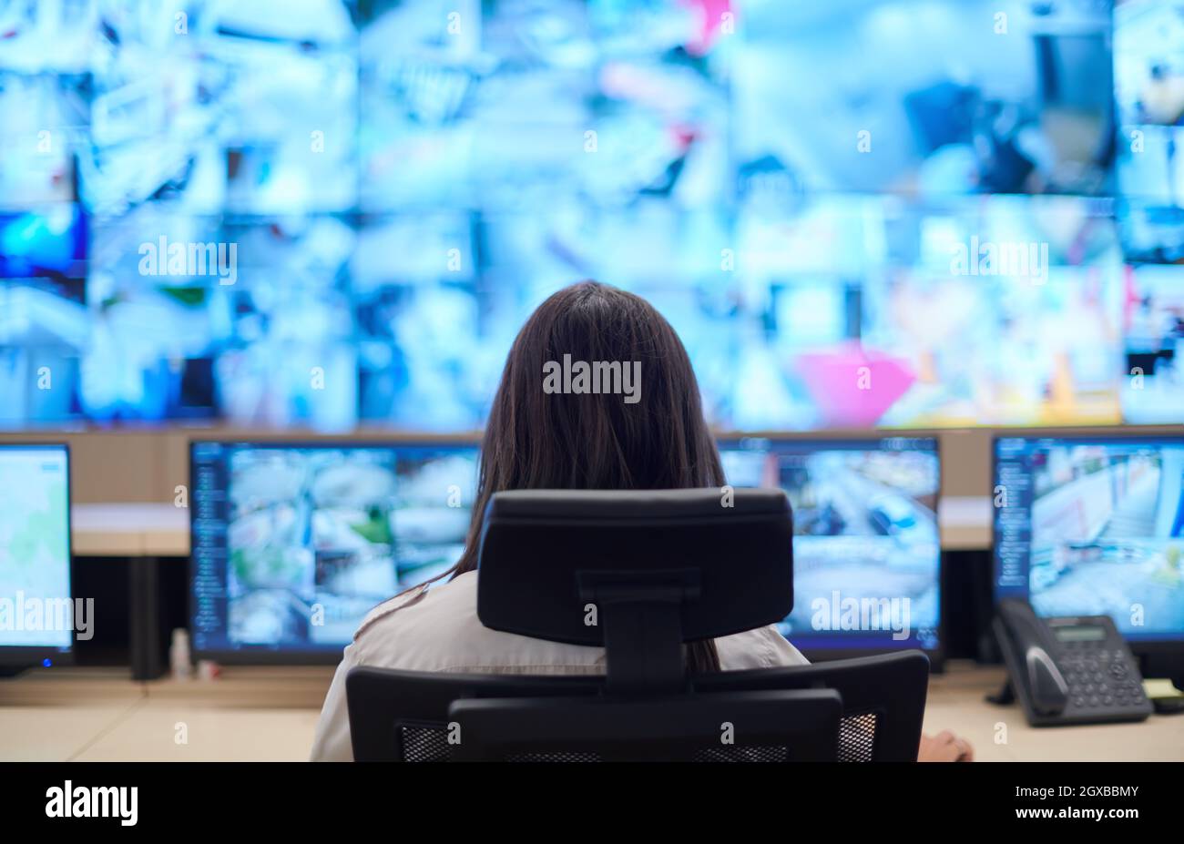 Female security operator working in a data system control room offices ...
