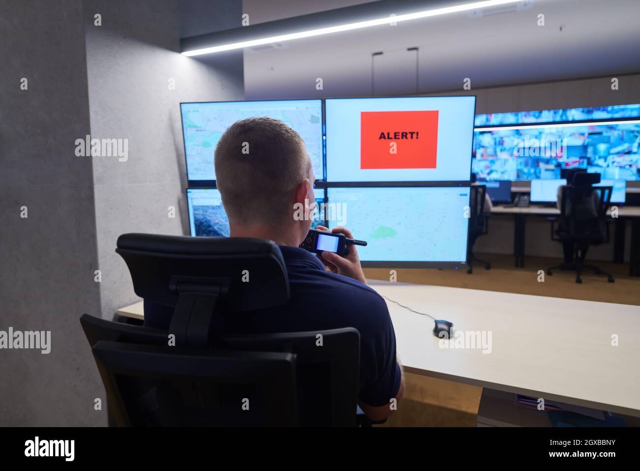 Male security operator working in a data system control room offices ...