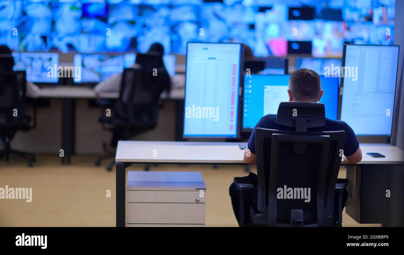Male security operator working in a data system control room offices ...
