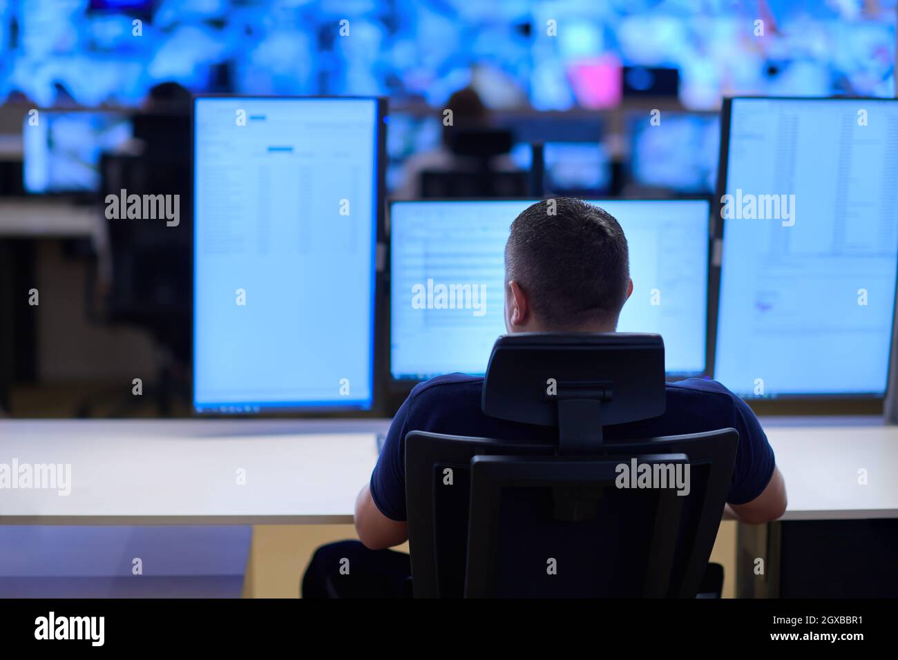 Male security operator working in a data system control room offices ...