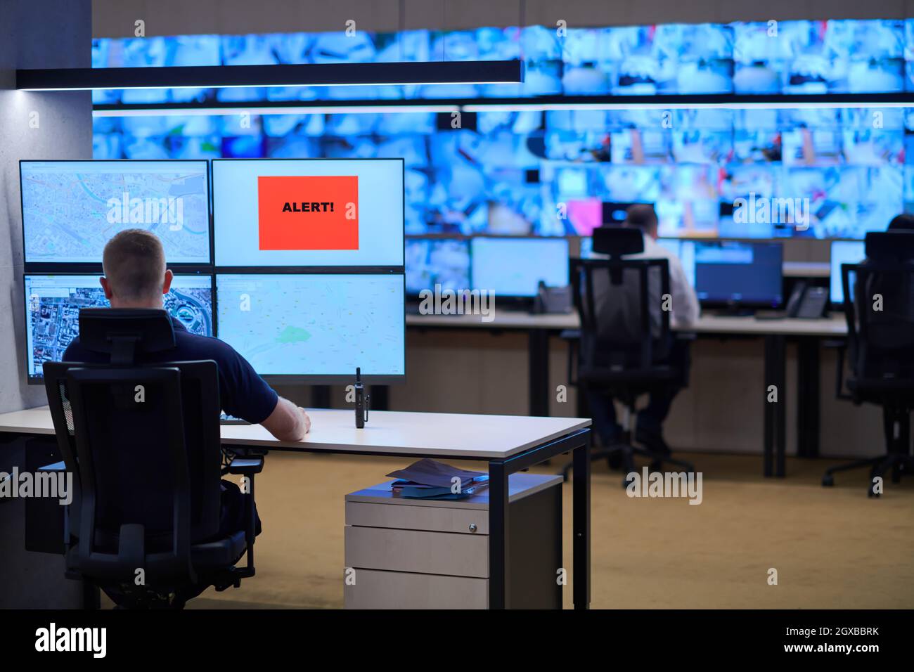 Male security operator working in a data system control room offices ...