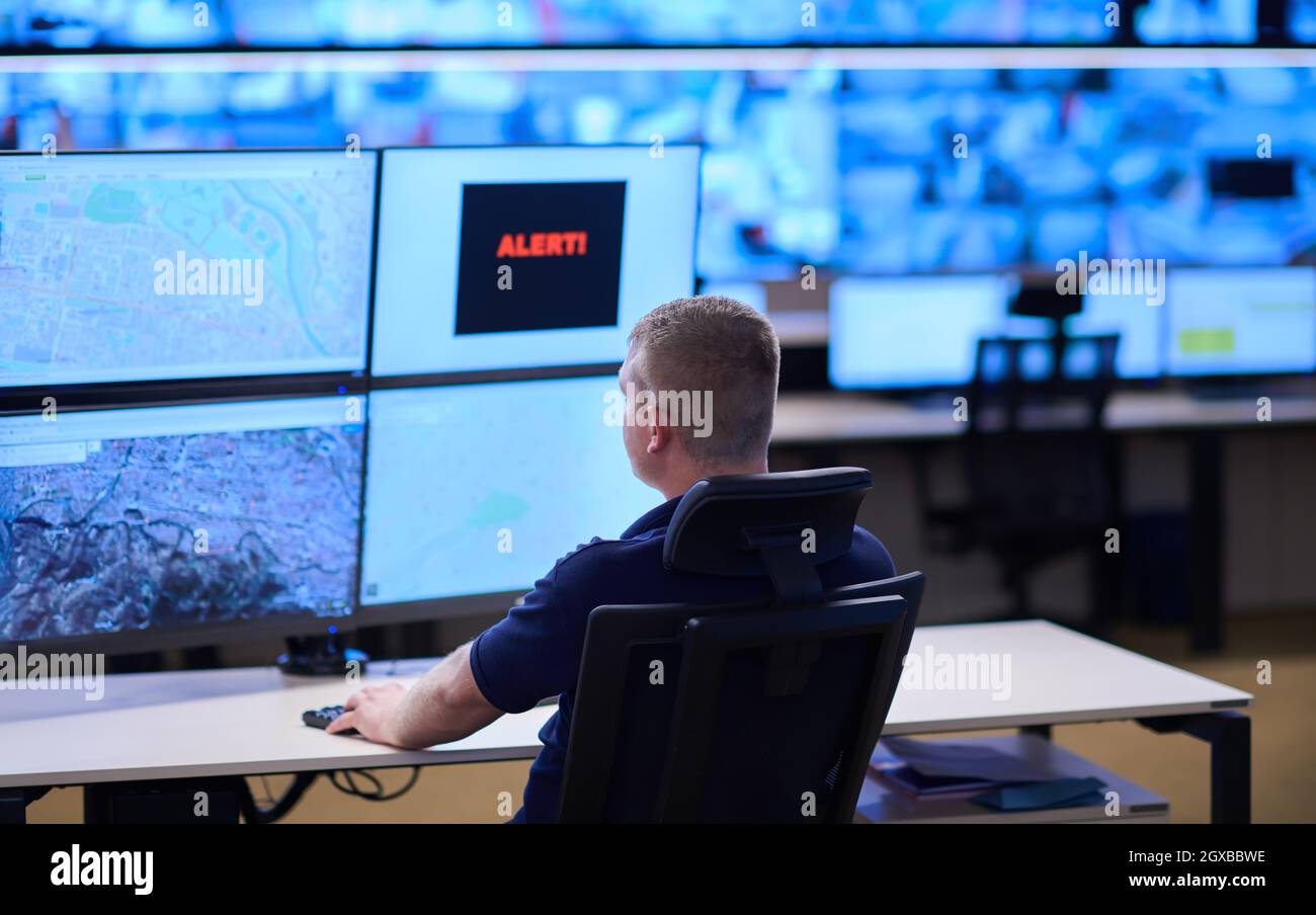 Male security operator working in a data system control room offices ...