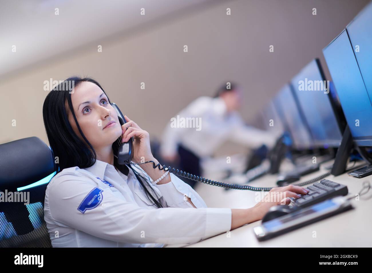 Female security guard operator talking on the phone while working at ...