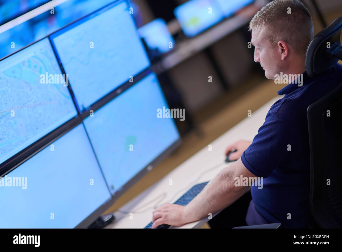 Male security operator working in a data system control room offices ...