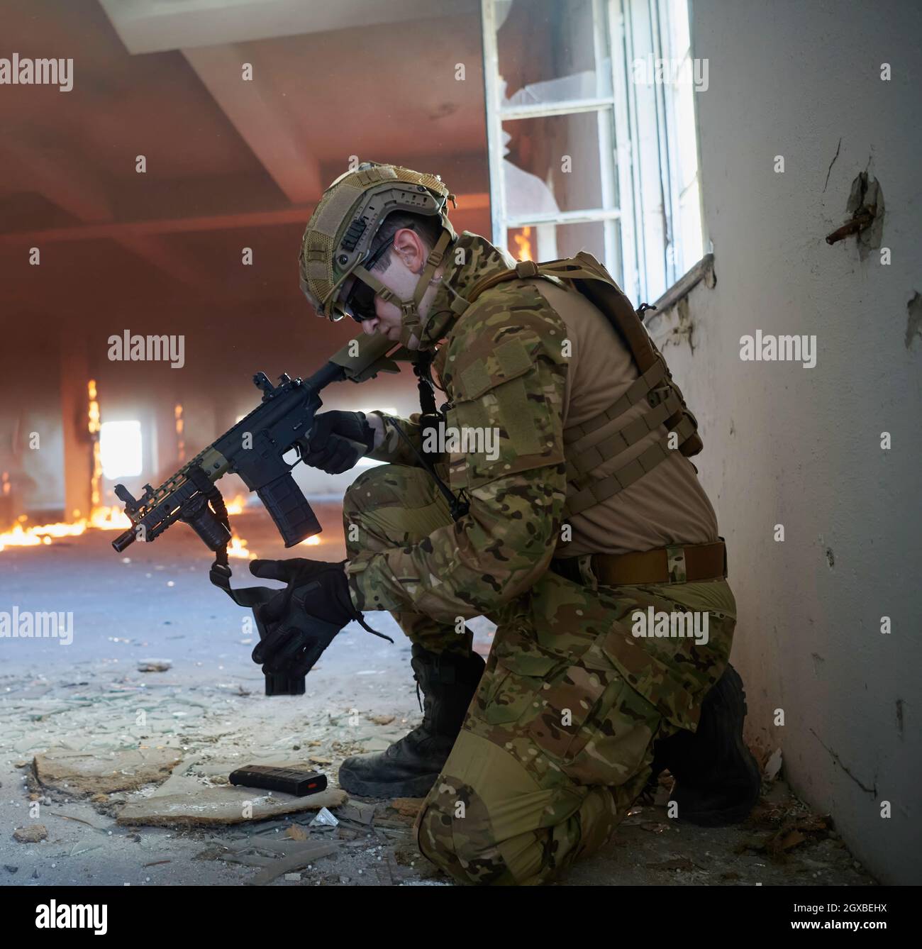 modern warfare soldier in action near window changing magazine and take ...