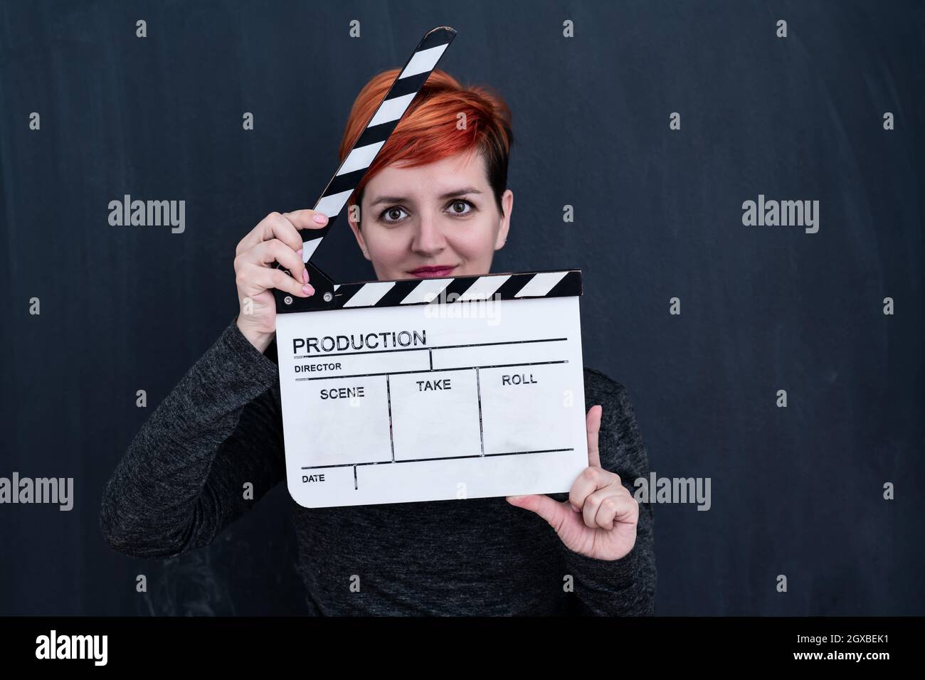 redhead woman on black chalkboard holding movie clapper cinema concept ...