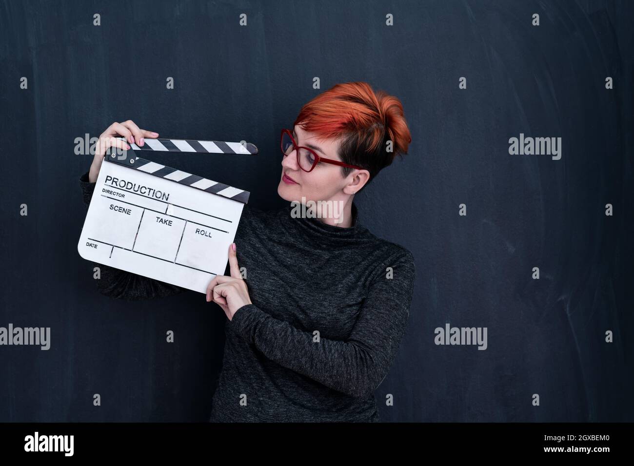 redhead woman on black chalkboard holding movie clapper cinema concept ...