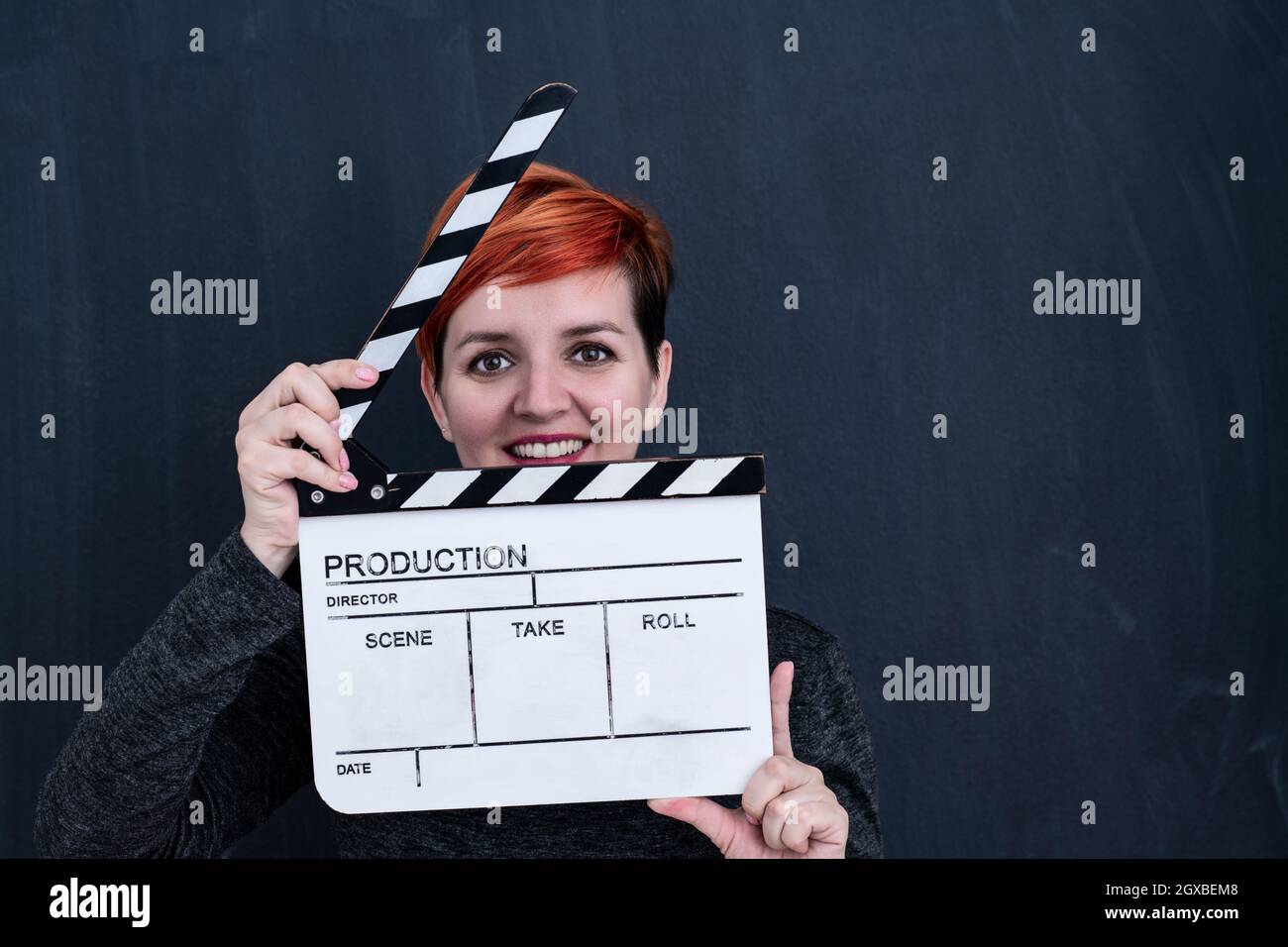 redhead woman on black chalkboard holding movie clapper cinema concept ...