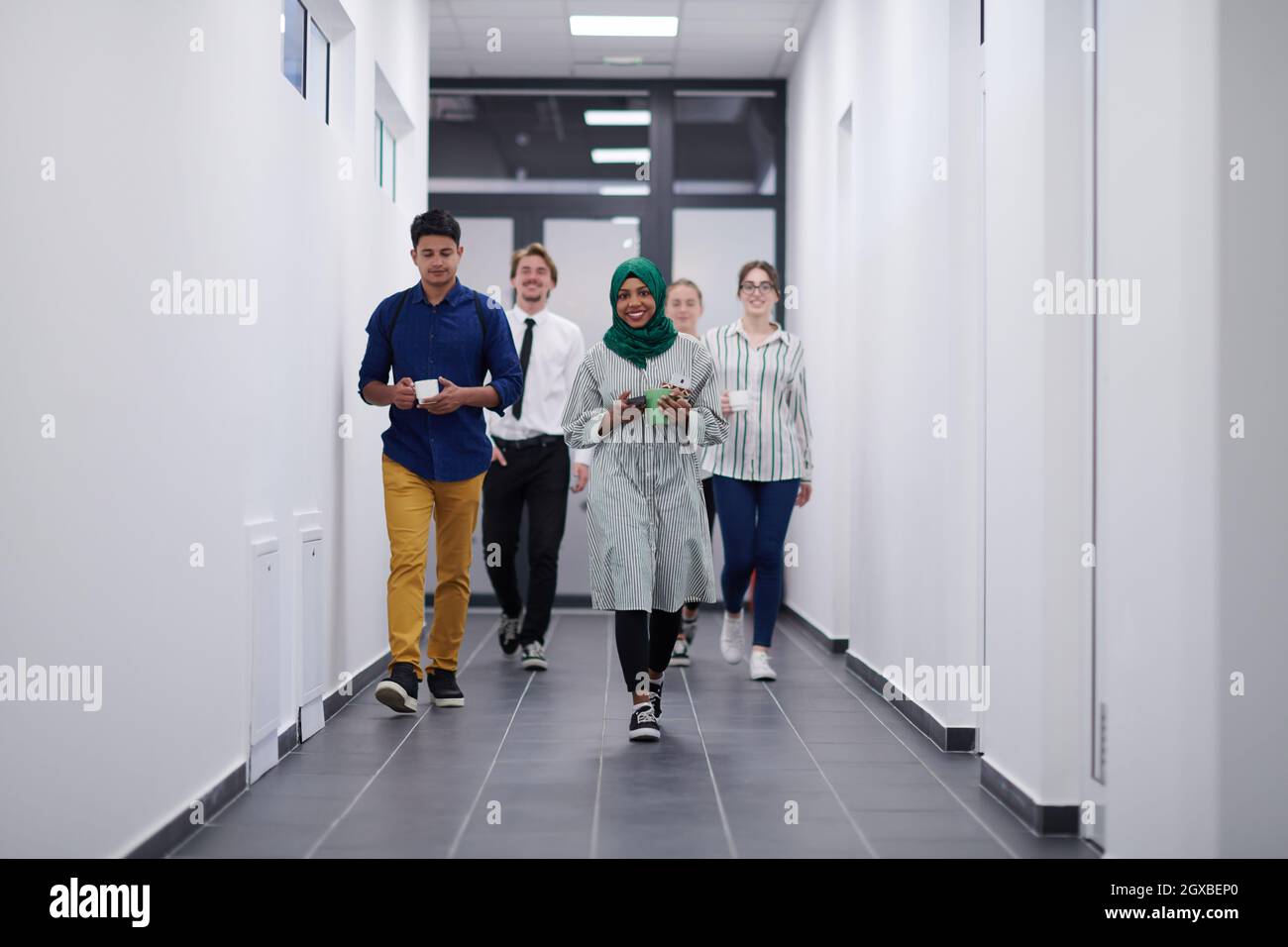 multi-ethnic startup business team walking through the hallway of the ...