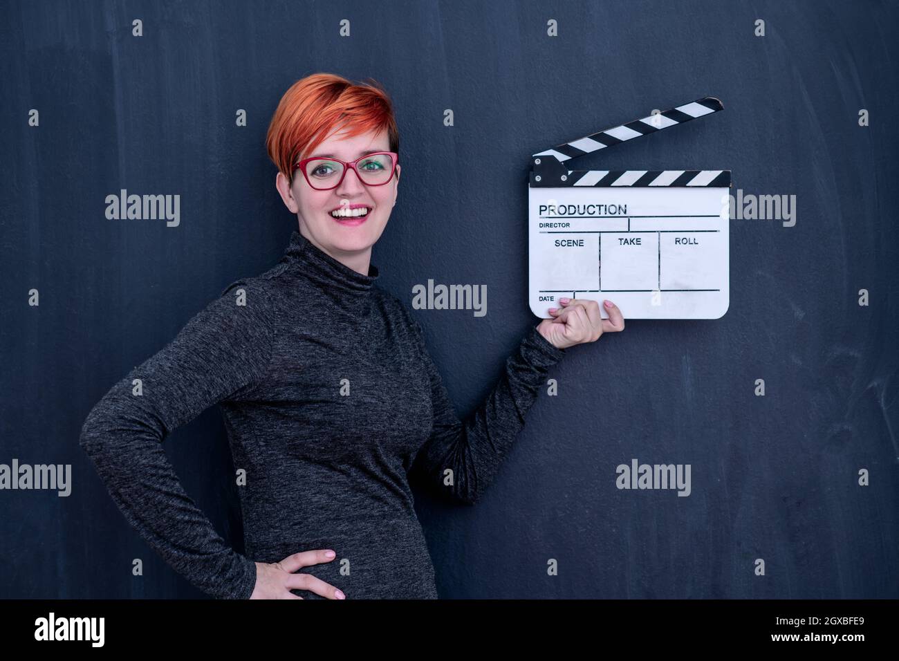 redhead woman on black chalkboard holding movie clapper cinema concept ...