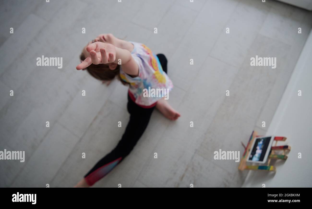 Little girl have online training over tablet and doing modern ballet ...