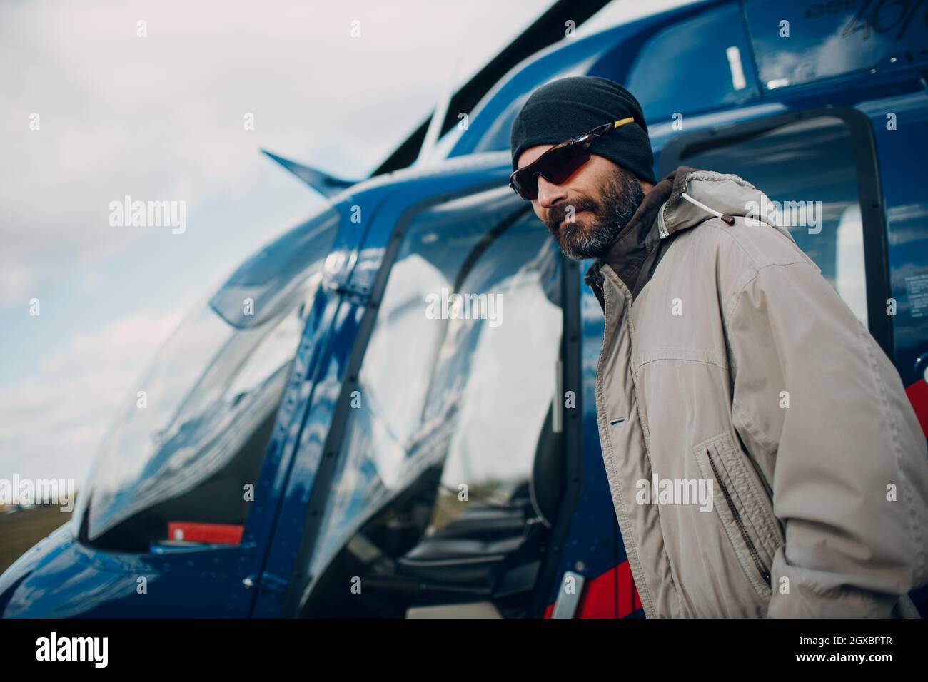 Portrait of helicopter pilot standing near vehicle in field airport ...