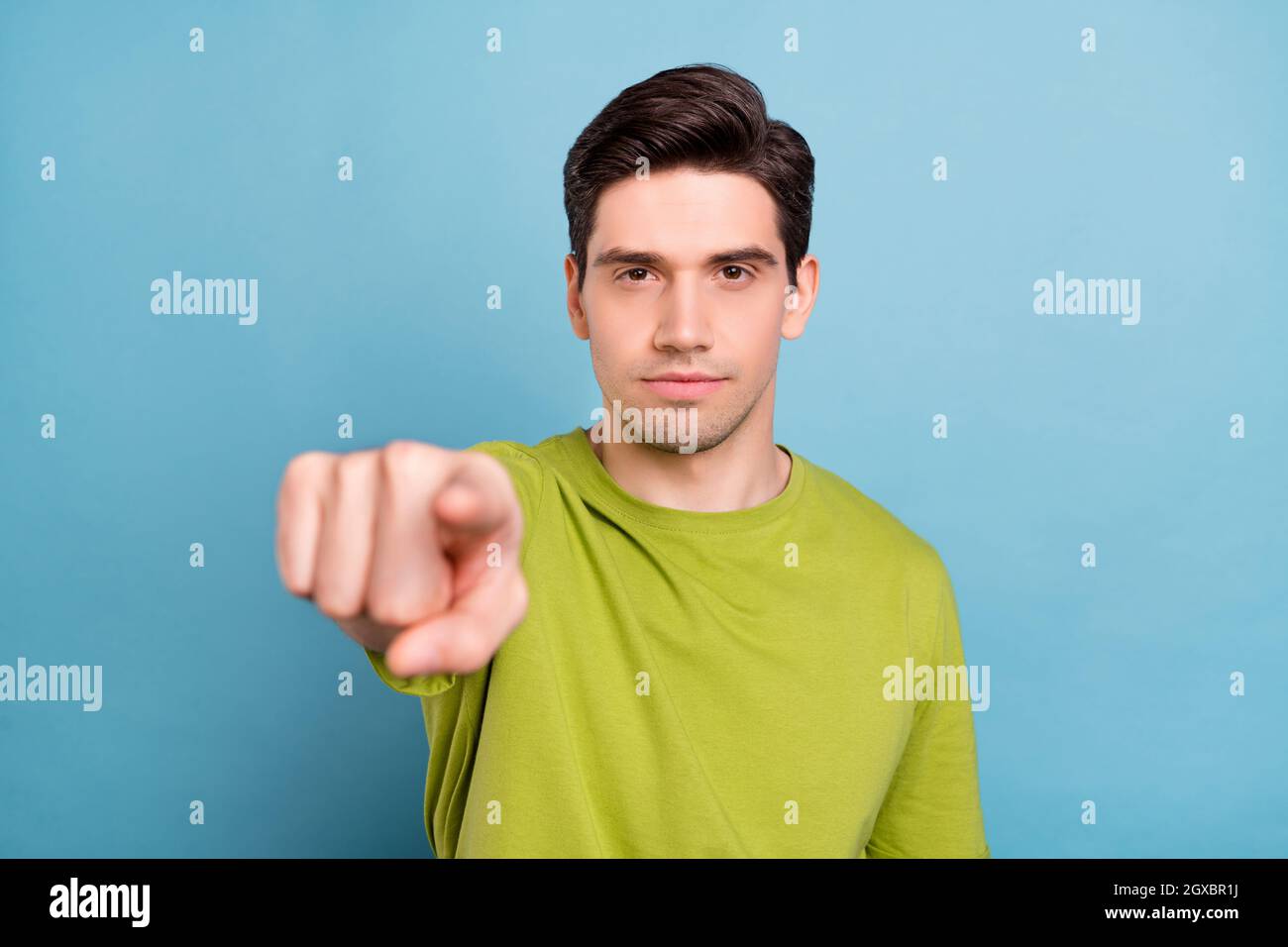 Photo of handsome serious young guy dressed green t-shirt pointing ...