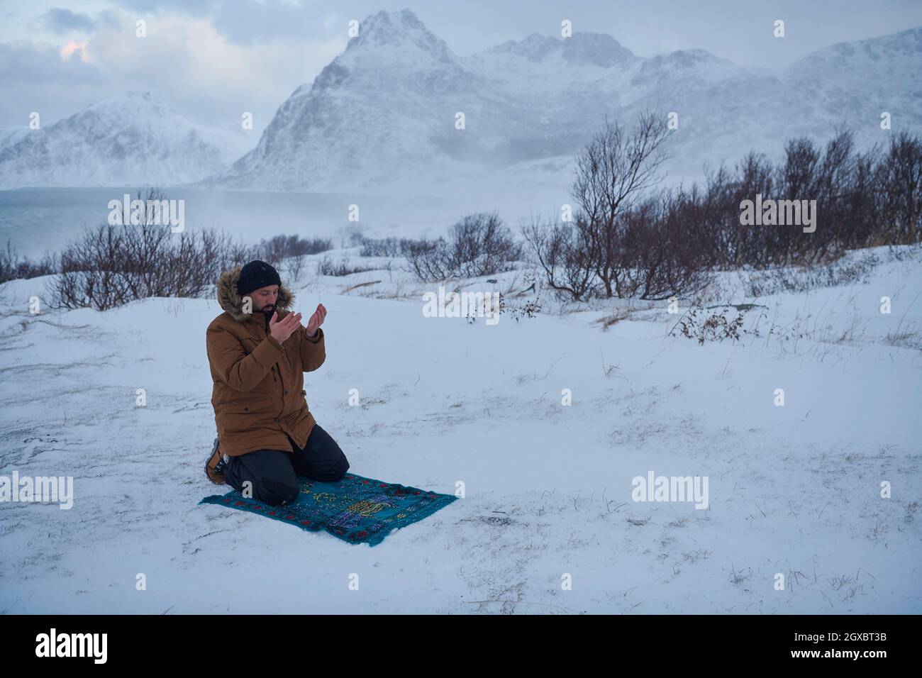 Muslim traveler praying in cold snowy winter day near the car in ...