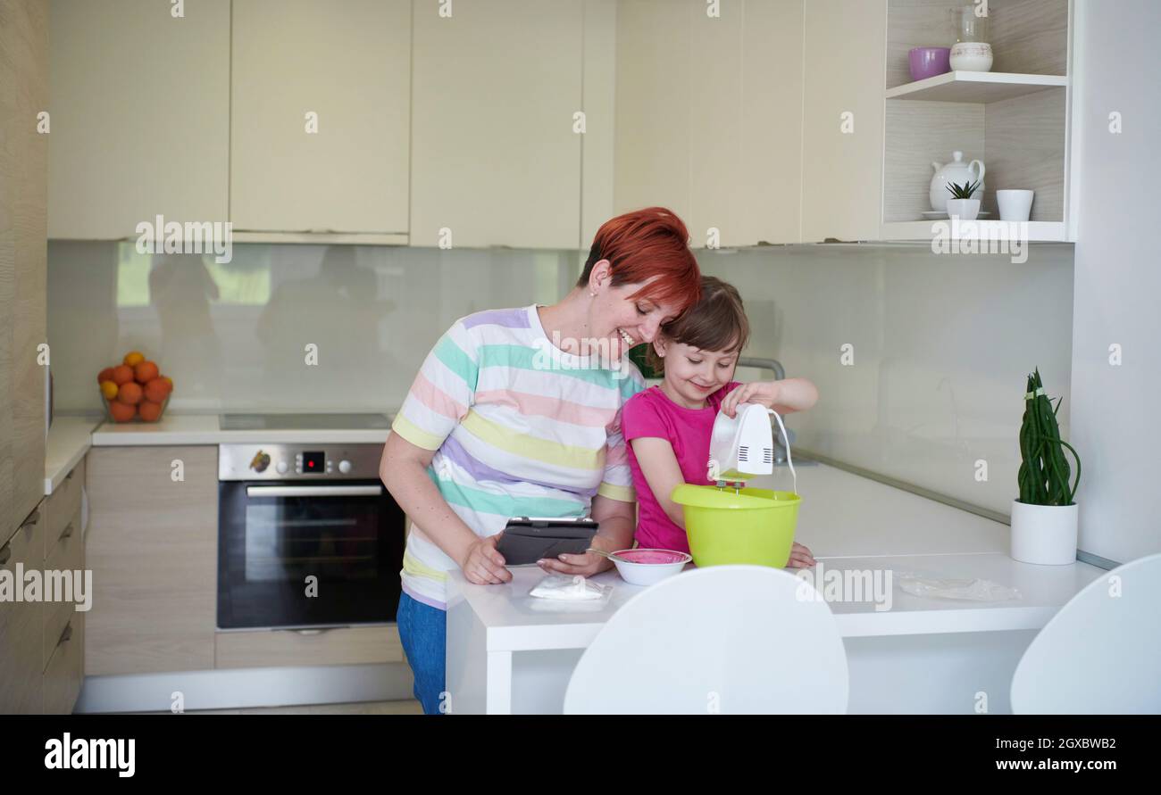 Happy family in the kitchen playing games and learning to cooking while staying at home during ...