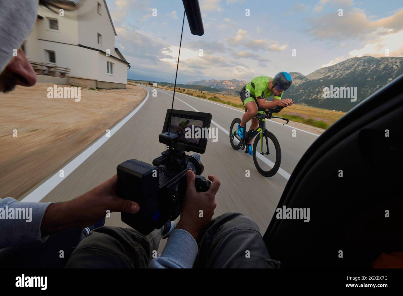 cinematographer with professional cinema camera taking sport action shot from moving car of ...