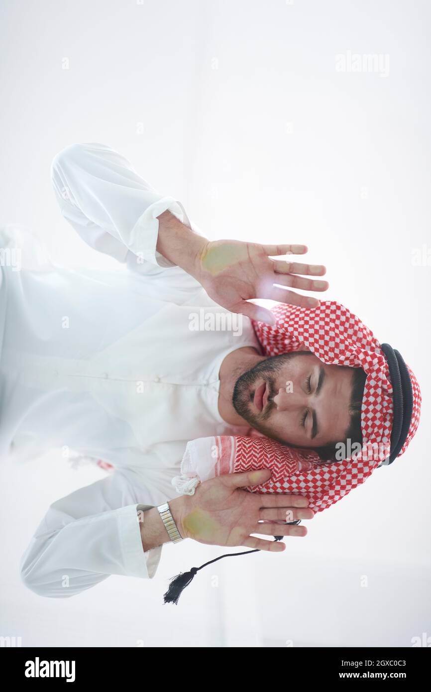 young arabian muslim man in traditional clothes praying on the glass ...