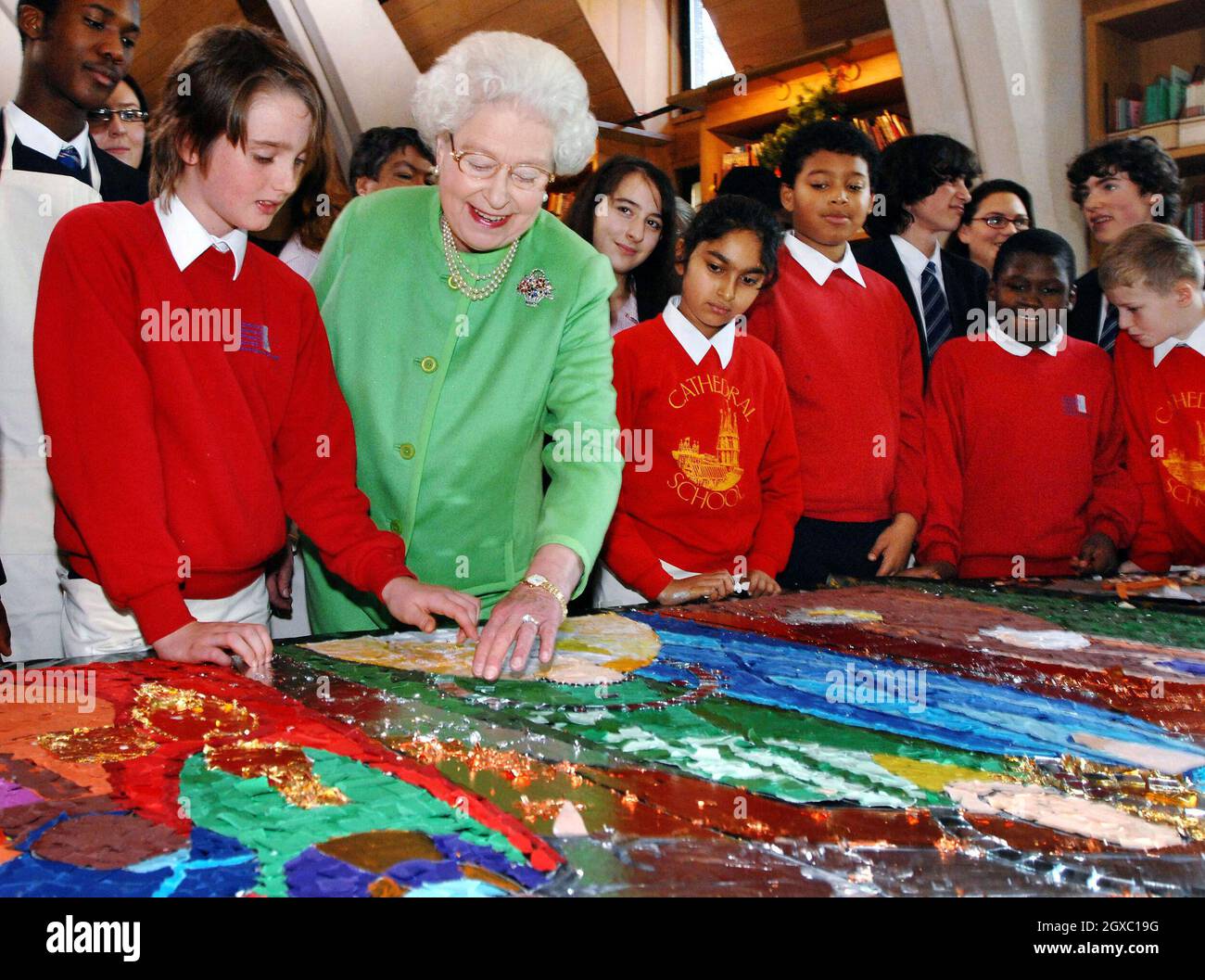Queen Elizabeth II lays small mirror tiles around the head of baby ...