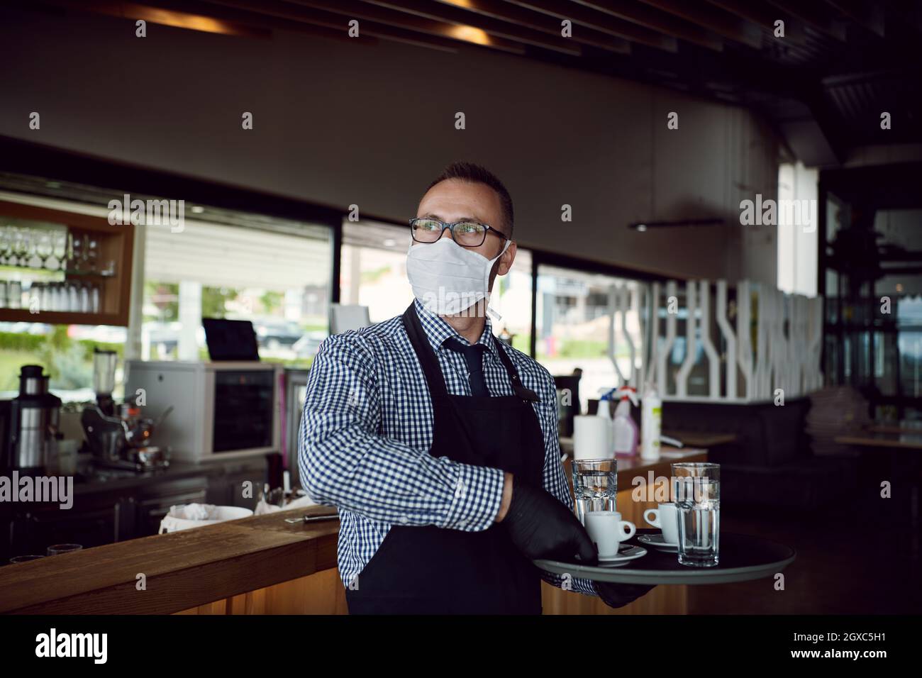 waiter in a medical protective mask serves the coffee in restaurant ...
