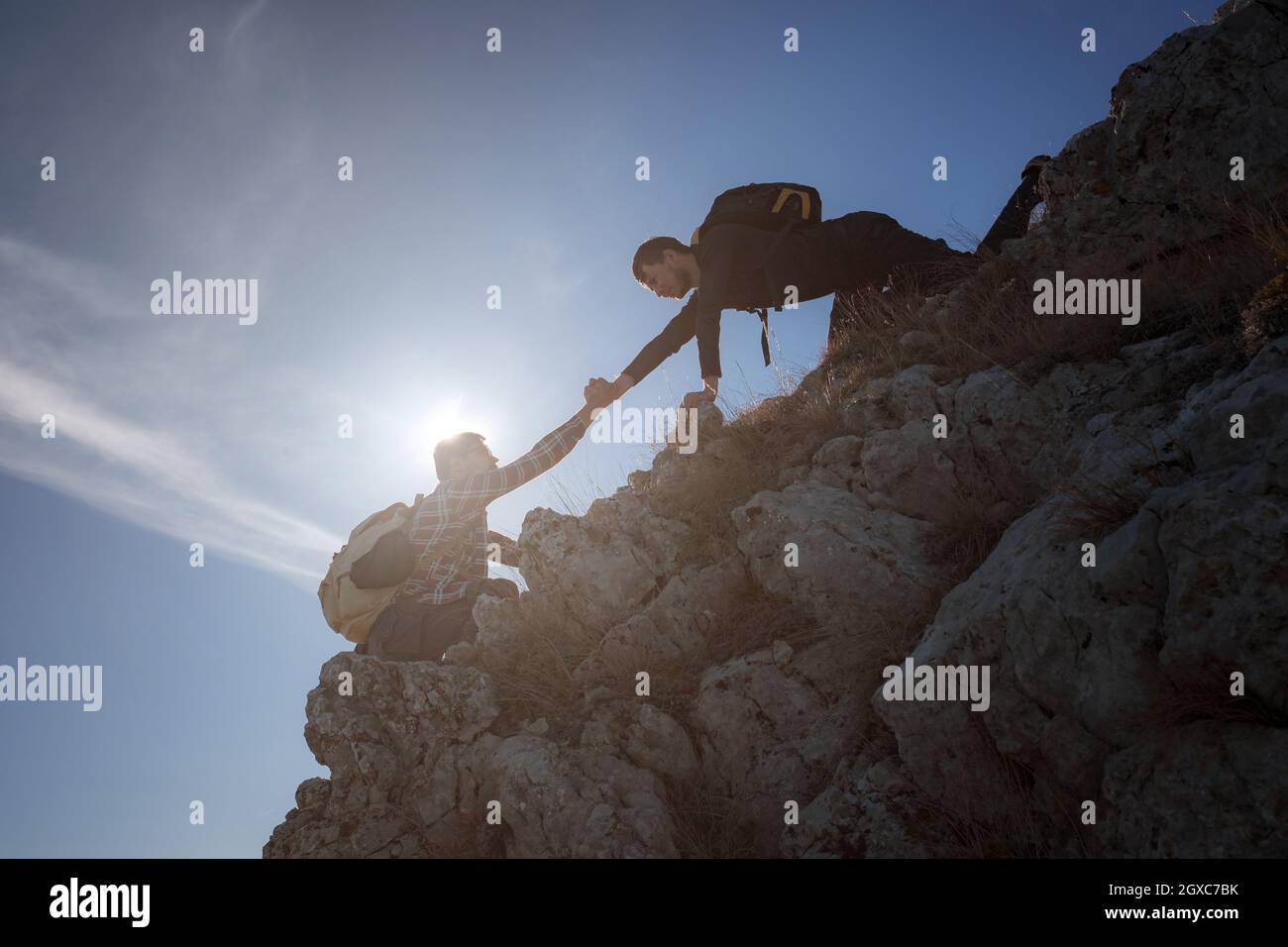 Help and assistance concept. Silhouettes of two people climbing ...