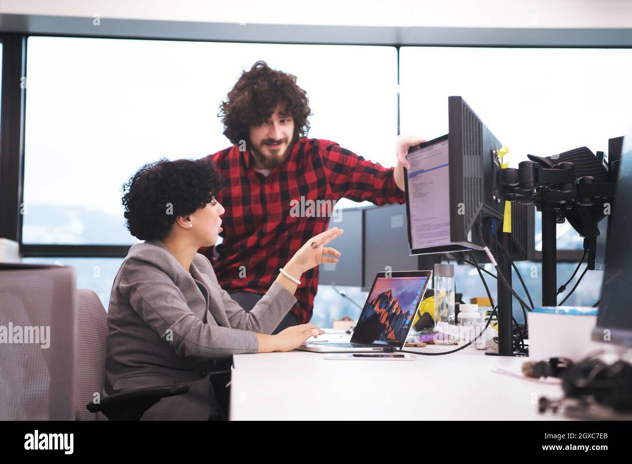 young software developers couple using laptop and desktop computer while writing programming ...