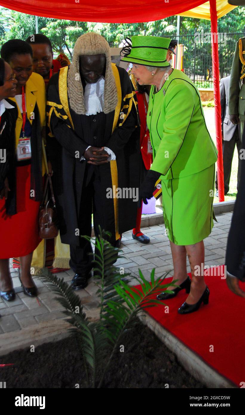 Queen Elizabeth ll plants a tree during a visit to the Ugandan ...