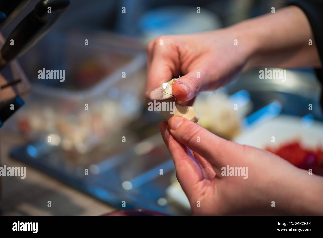 Woman peeling garlic in the kitchen. Close up of a woman working in the ...