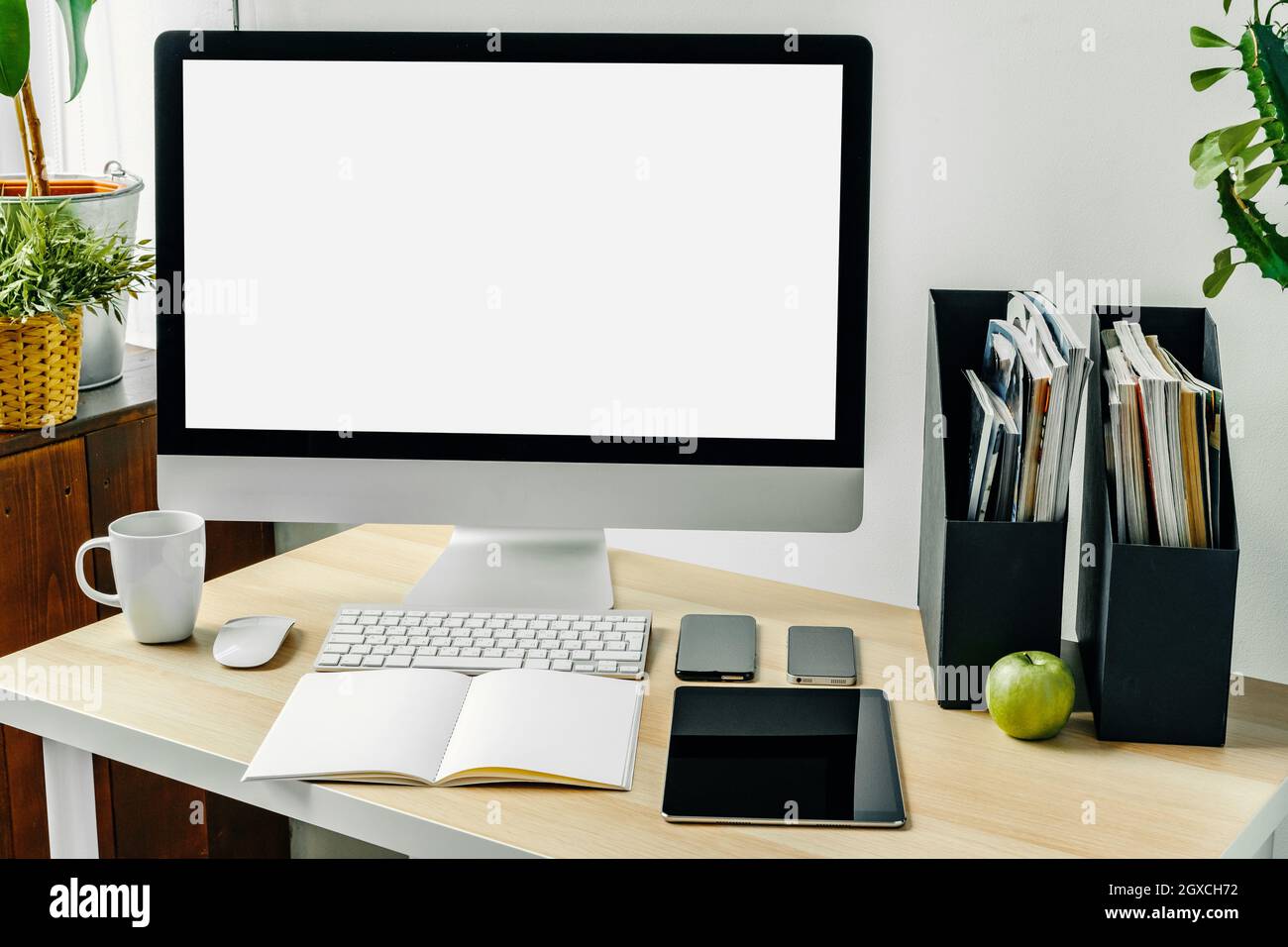 Computer monitor with mockup white screen on office table with supplies ...