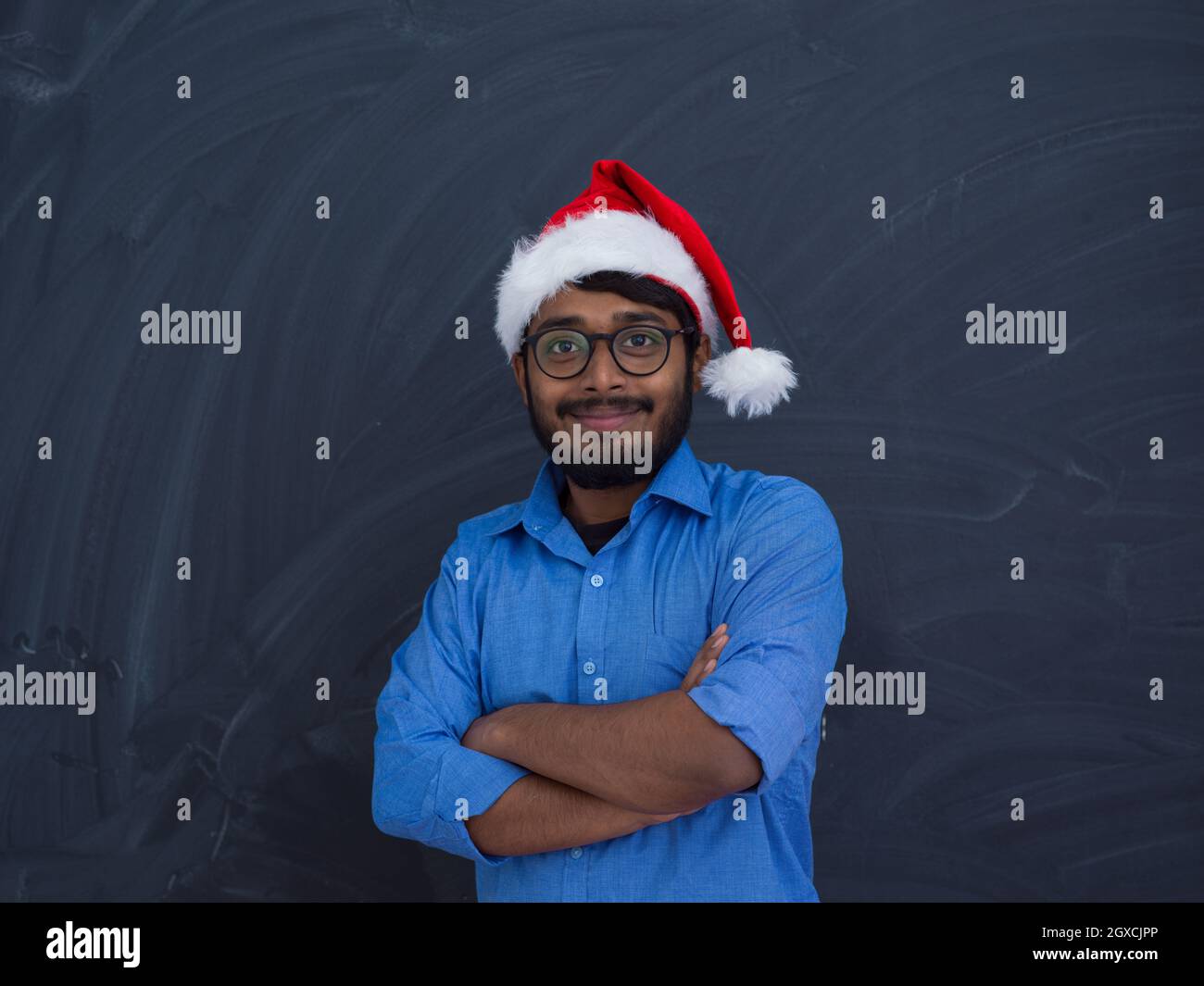 Indian man wearing traditional Santa Claus hat on chalkboard background ...