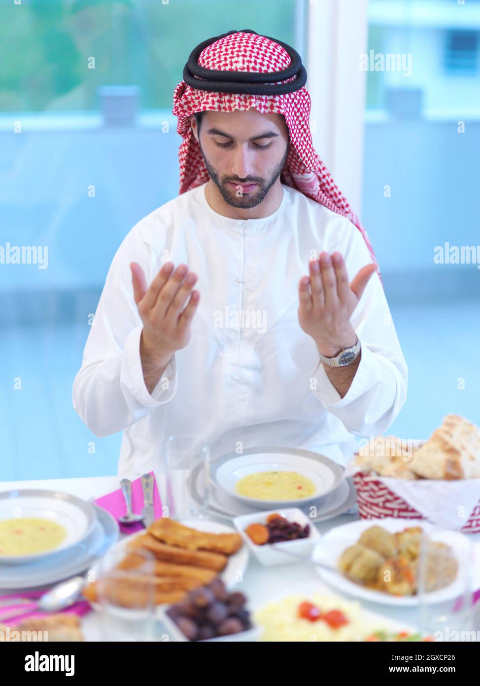 young arabian muslim man making traditional prayer to God, keeps hands ...