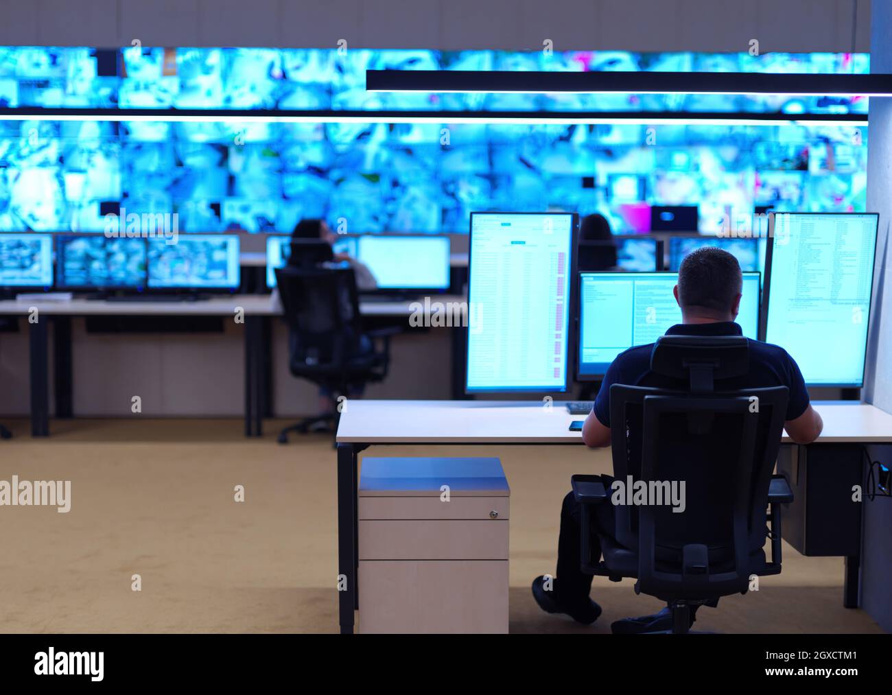 Male security operator working in a data system control room offices ...