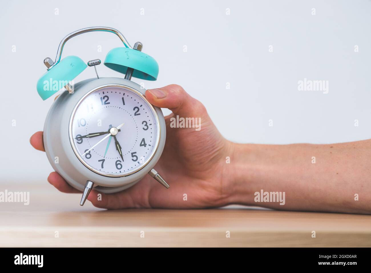 Male hand is holding a retro styled white alarm clock, isolated Stock ...
