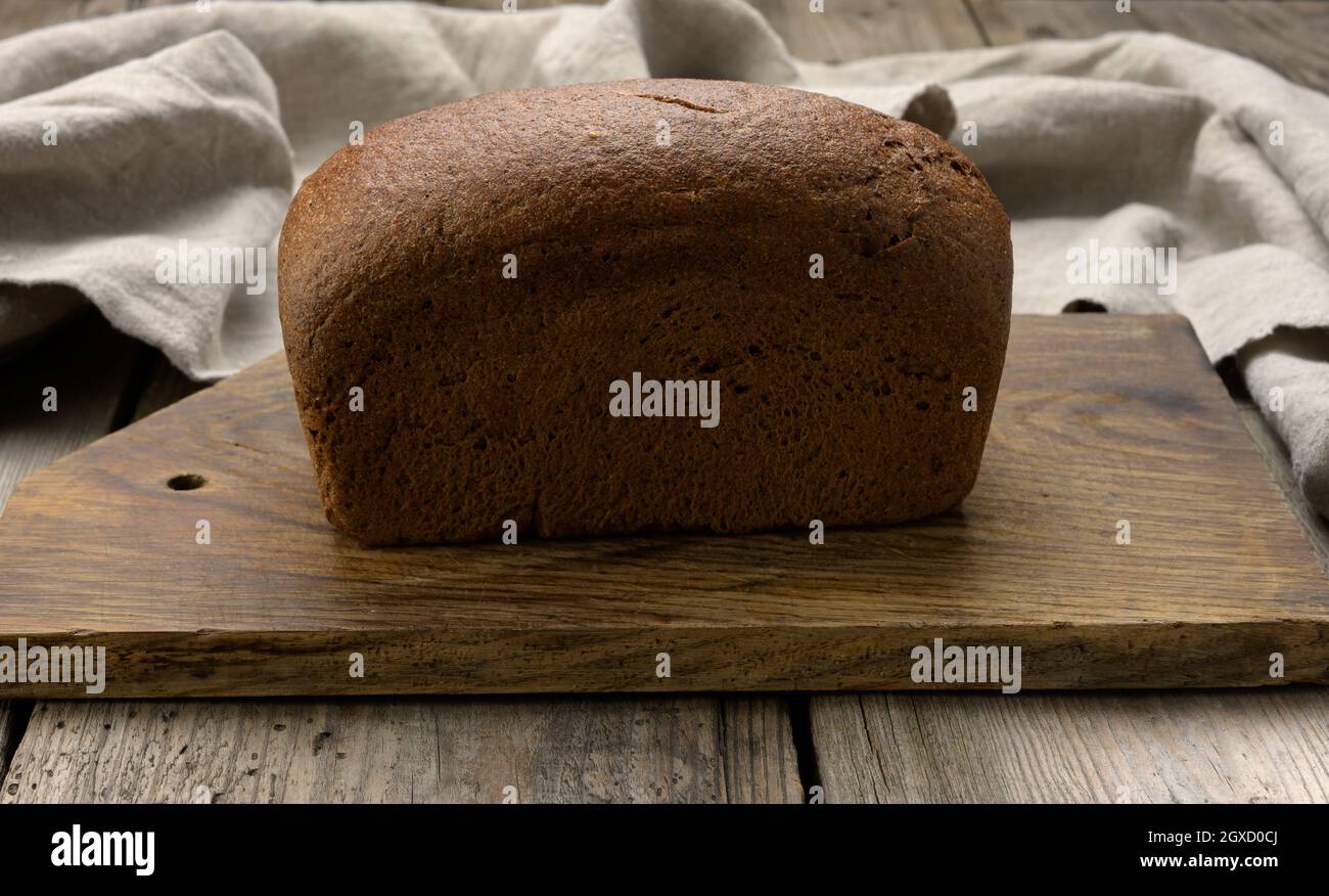 baked rectangular rye flour bread on brown board, healthy food, top ...