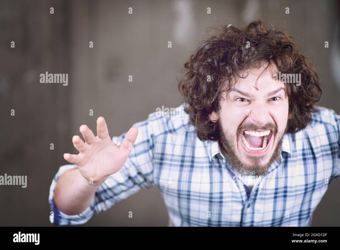 young successful casual businessman screaming in front of a concrete ...