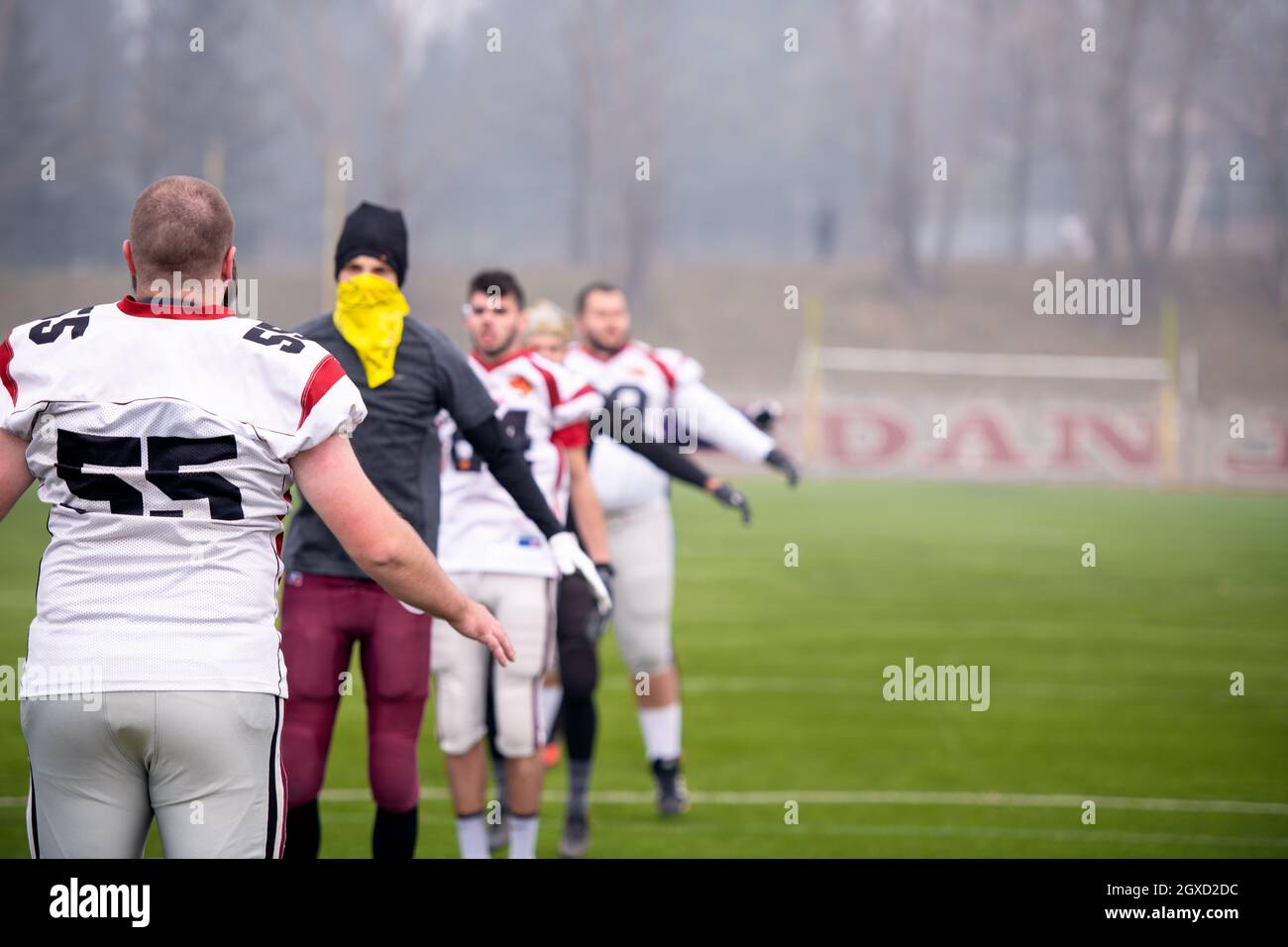 group of young american football players warming up and stretching ...