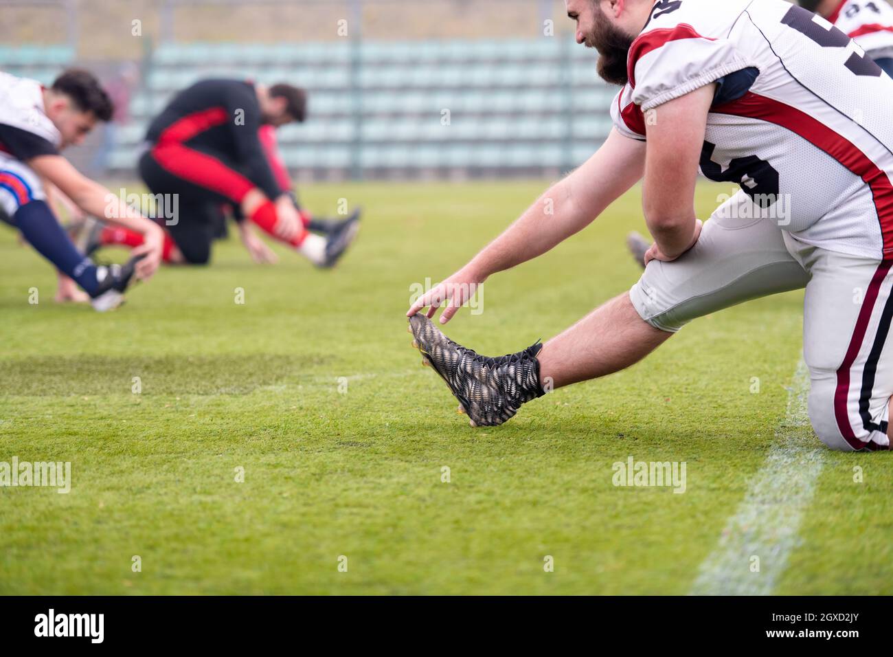 group of young american football players warming up and stretching ...
