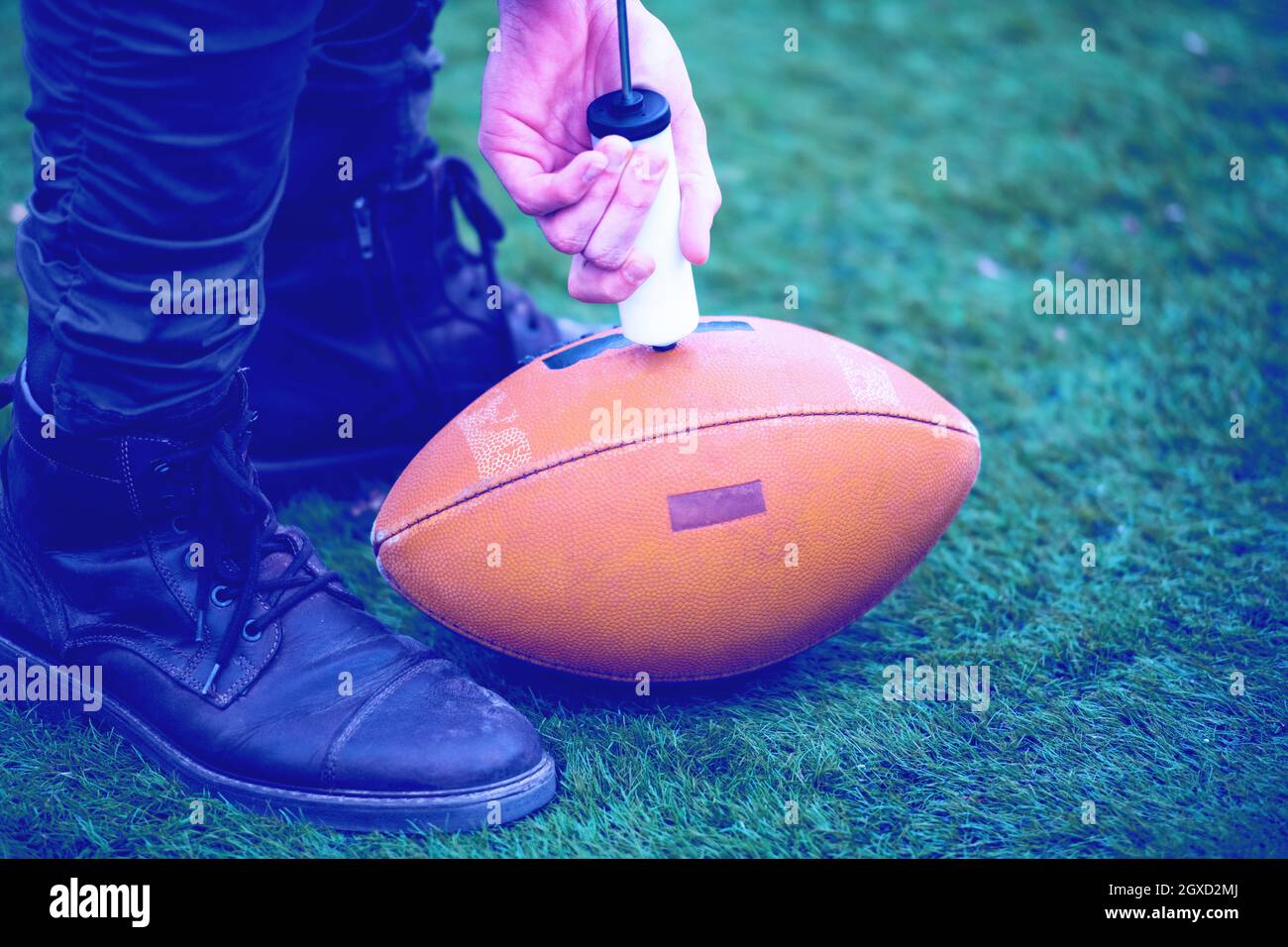 close up shot of man on the field pumping air into a professional ball ...