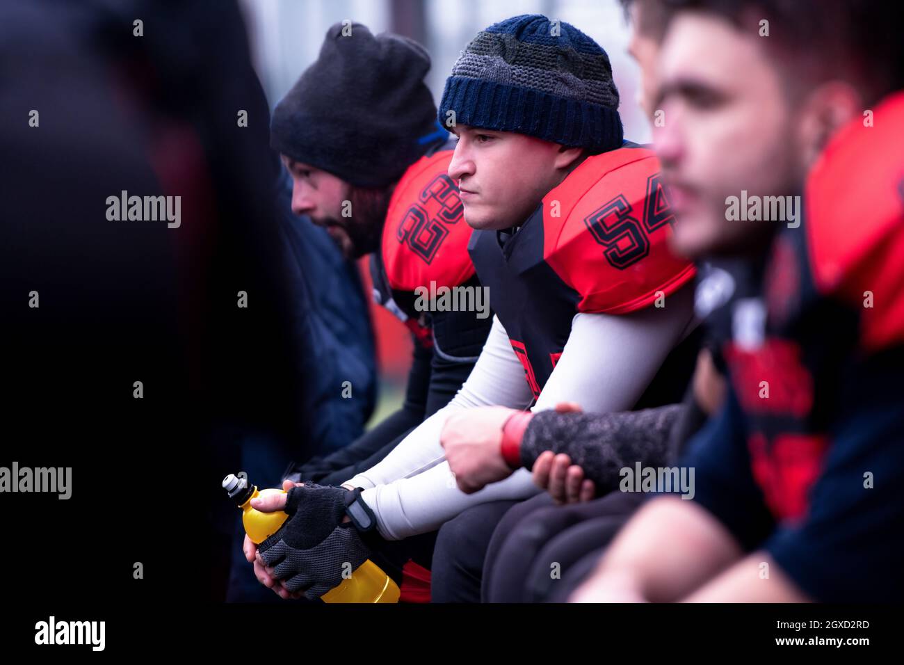 A tired american football player sitting on a bench while resting with ...