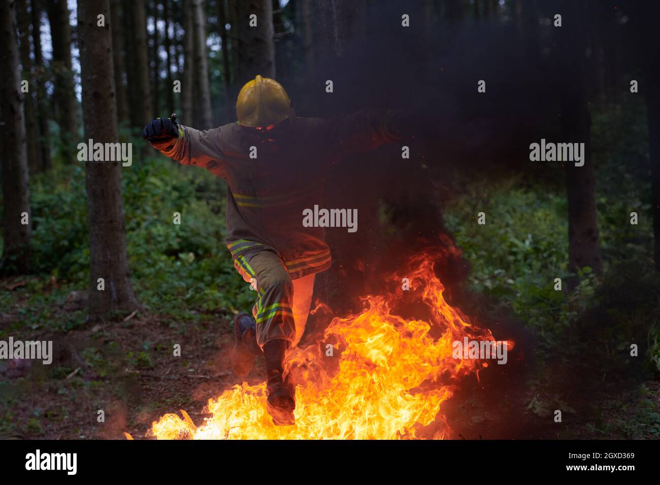 firefighter hero in action danger jumping over fire flame to rescue and ...