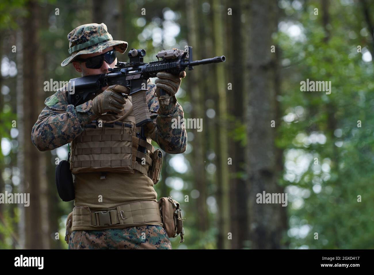 modern warfare soldier in action aiming at weapon laser sight optics in combat position while ...