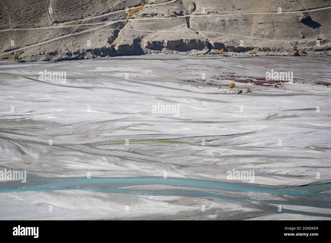 Bright narrow river flowing through snowy valley surrounded by steep ...