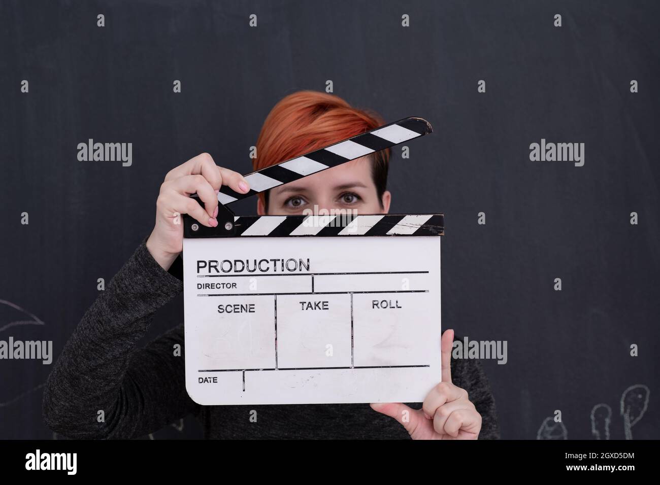 redhead woman on black chalkboard holding movie clapper cinema concept ...