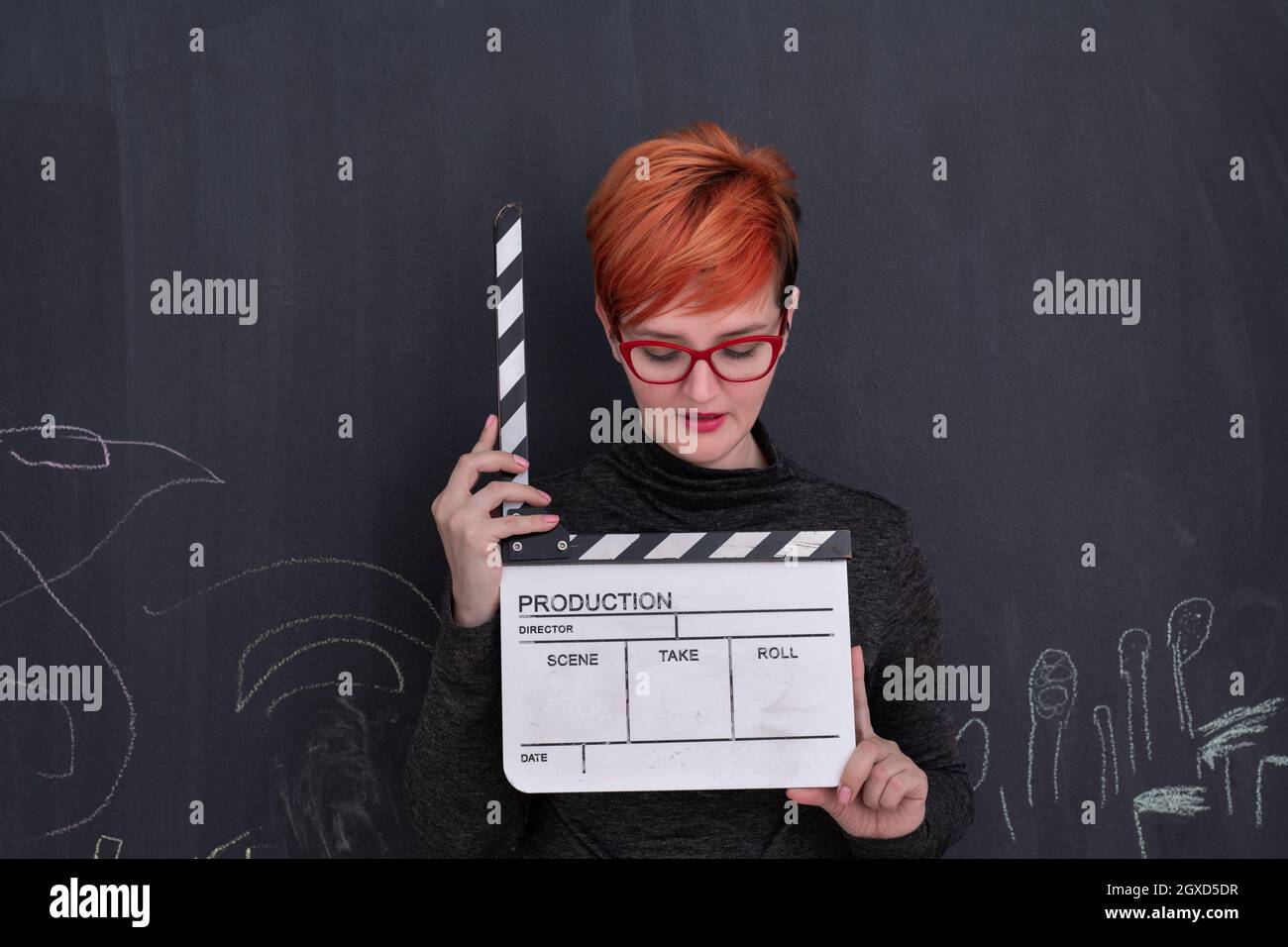 redhead woman on black chalkboard holding movie clapper cinema concept ...