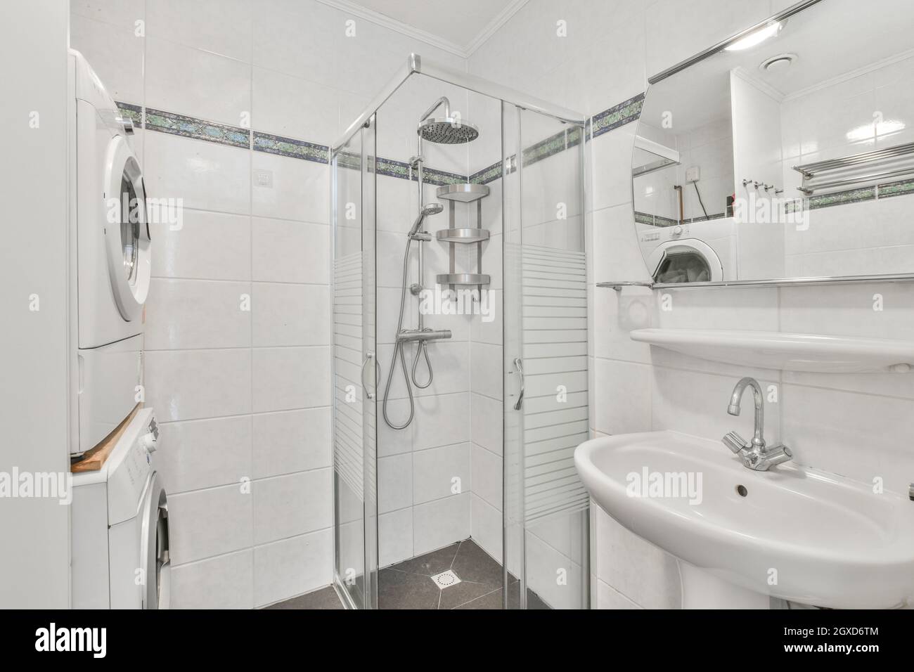 Shower cabin and washing machines in modern bathroom with white tiled ...