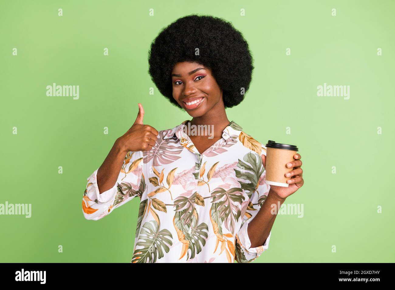Photo of positive girl hold coffee cup raise thumb up wear floral print ...