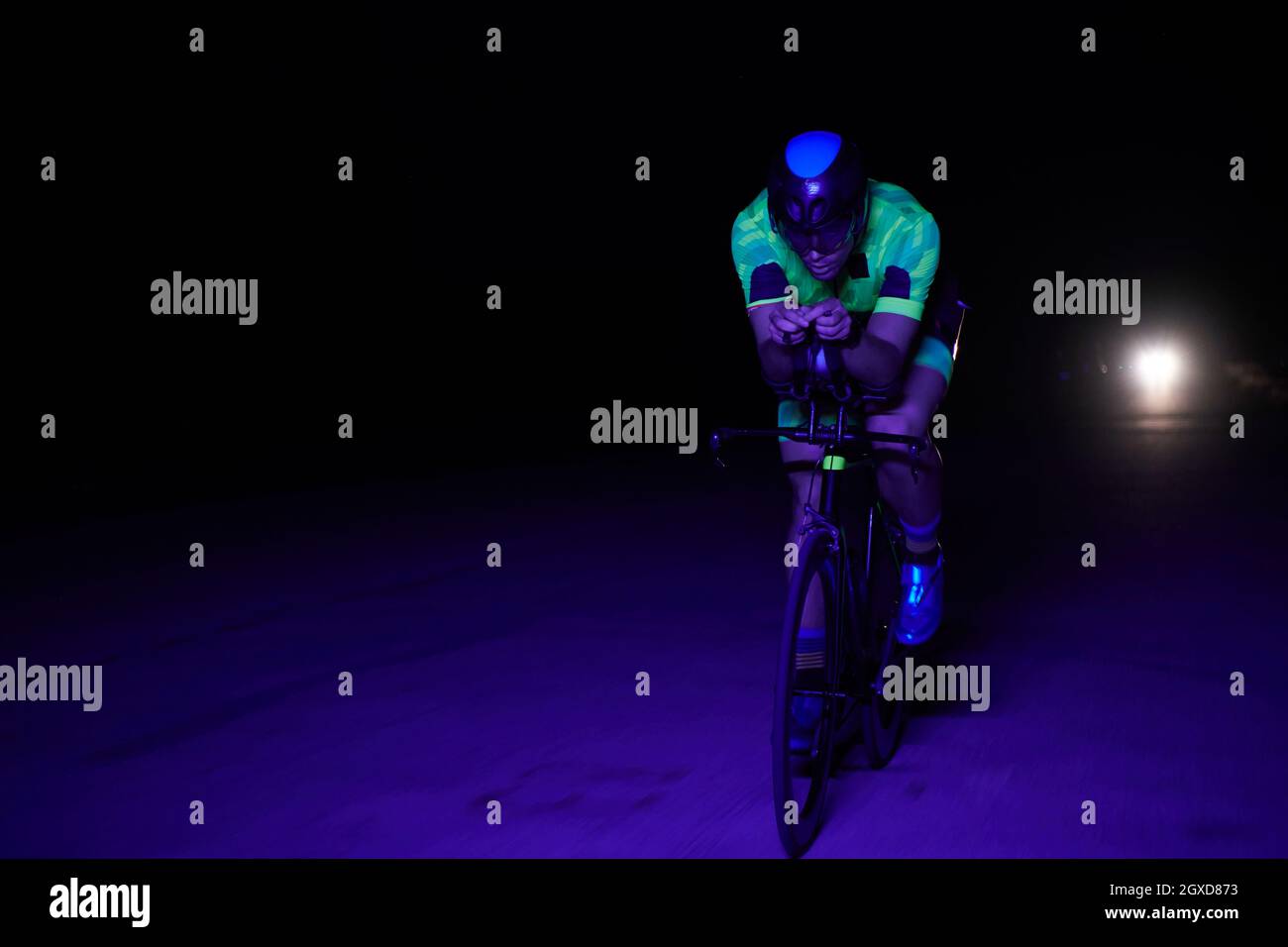 triathlon athlete cycling fast riding professional racing bike at night ...